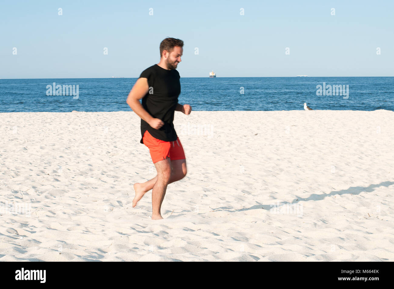 Young man running on beach black hi-res stock photography and images ...