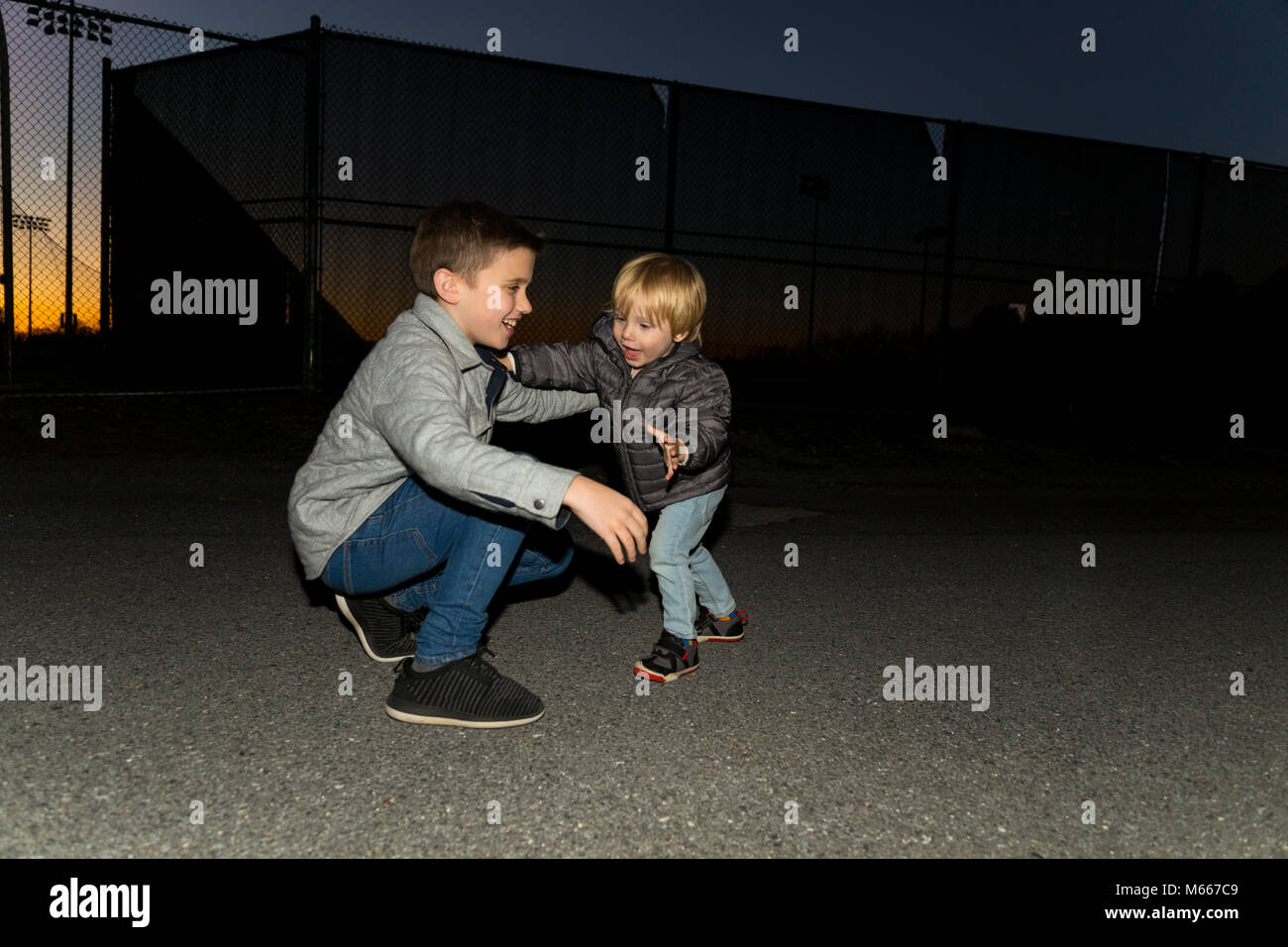 Two Young Boys Play With One Another In Their Backyard On A Cool Fall ...