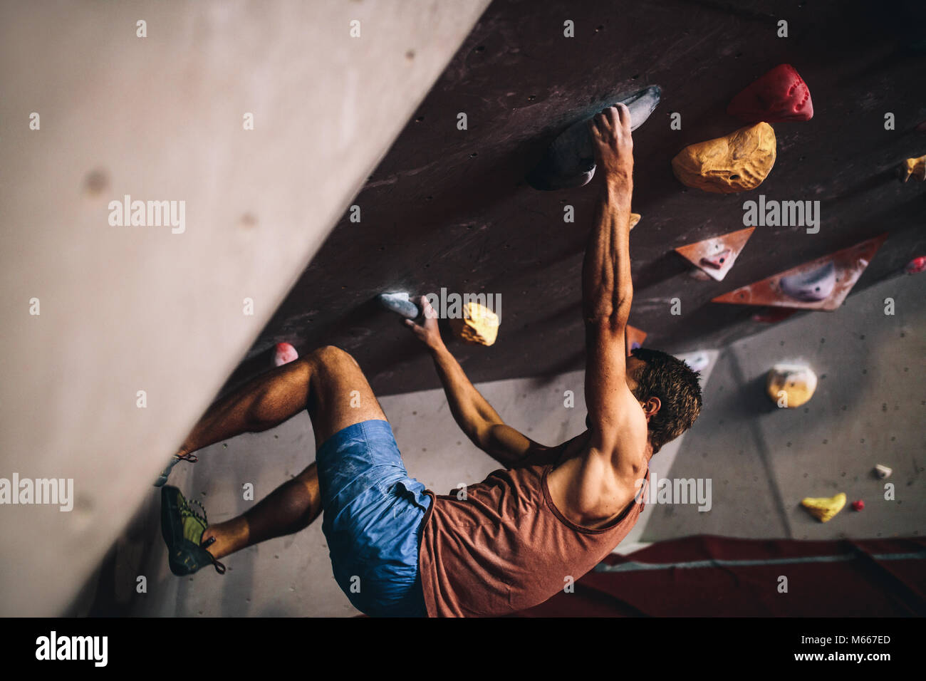 Athletic man bouldering at an indoor climbing centre. Professional ...