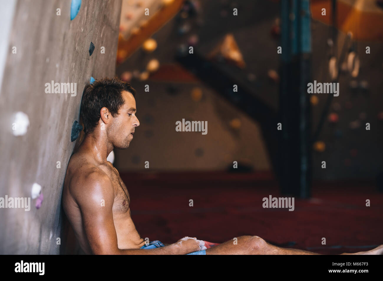 Tired man taking rest after climbing bouldering wall at a wall climbing ...