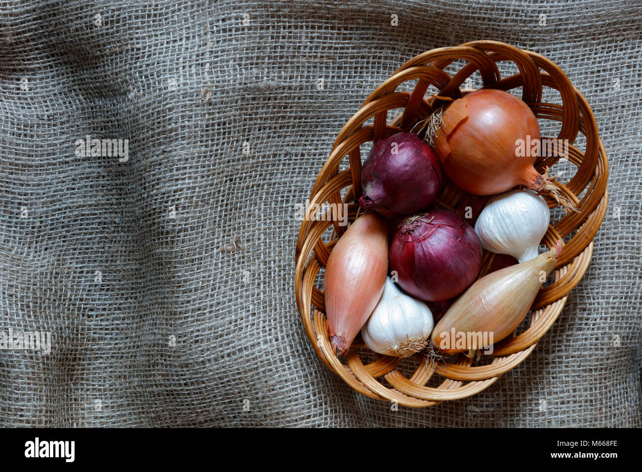 Garlic, French Echalion Shallots and red and brown onions in a wicker ...