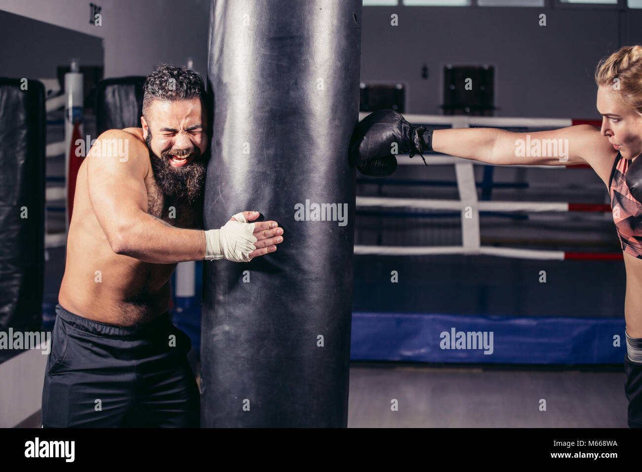 woman working out with boxing gloves and punching bag with her trainer ...