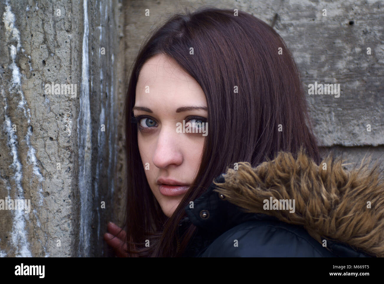 Scared young woman hugs the wall Stock Photo - Alamy
