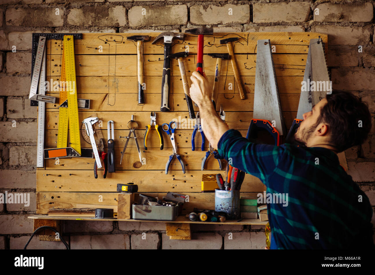 man takes hammer from wall with tools Stock Photo - Alamy