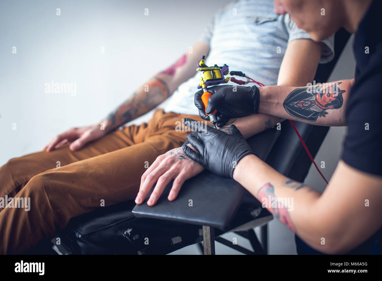 Master tattoo artist in gloves makes tattoo Stock Photo - Alamy