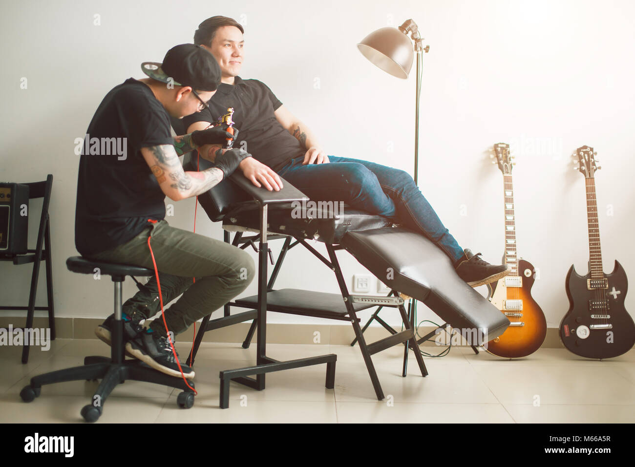 Tattoo machine make drawing on male hand Stock Photo - Alamy