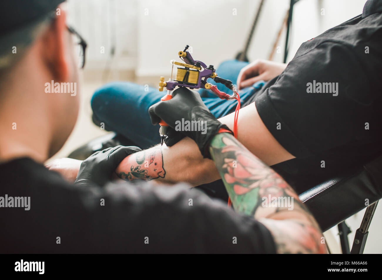 Tattoo machine make drawing on male hand Stock Photo - Alamy