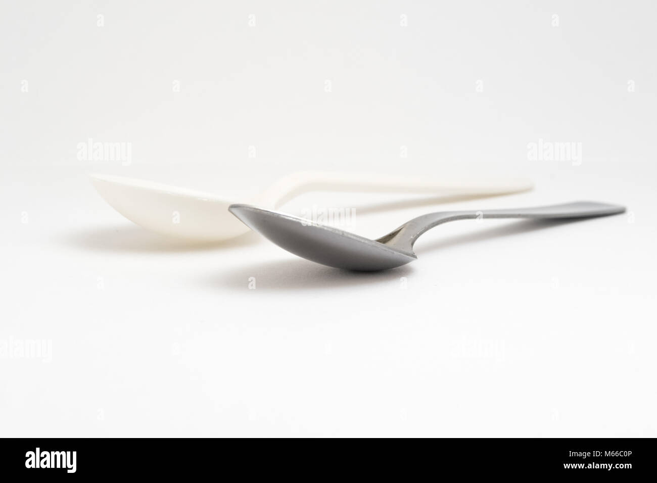 Recycling concept. A metal spoon and a plastic spoon side by side. The ...