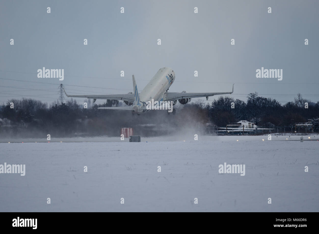 Snow covered airport. Flybe Embraer ERJ-195 taking off at London ...
