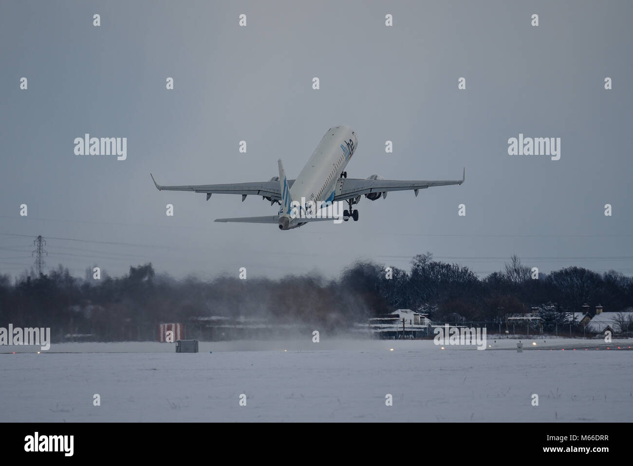 Snow covered airport. Flybe Embraer ERJ-195 taking off at London ...