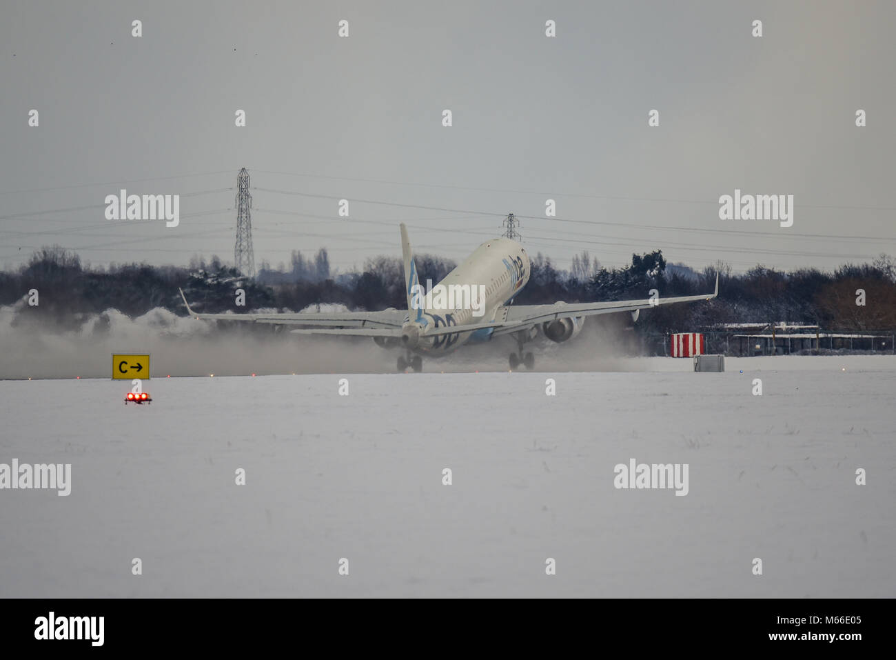Snow covered airport. Flybe Embraer ERJ-195 taking off at London ...