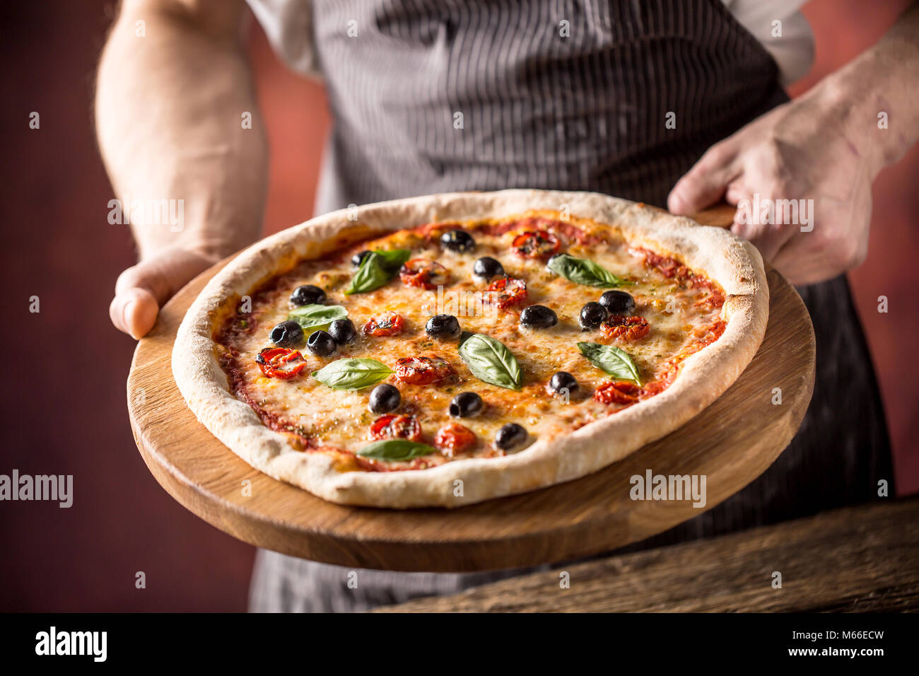Chef and pizza. Chef offering pizza in hotel or restaurant Stock Photo ...