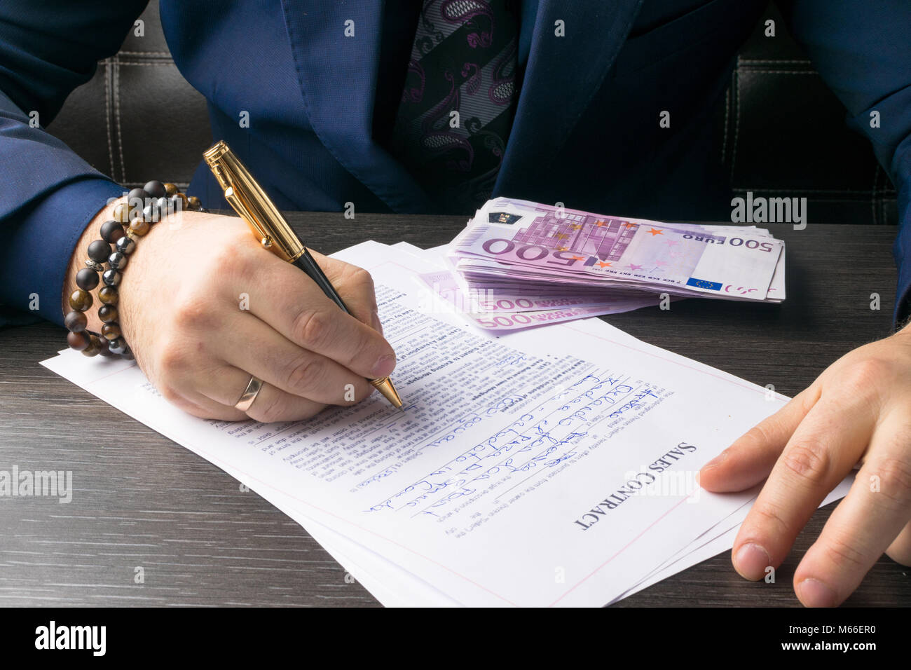 Business man writing a payment check contract at the table and working ...