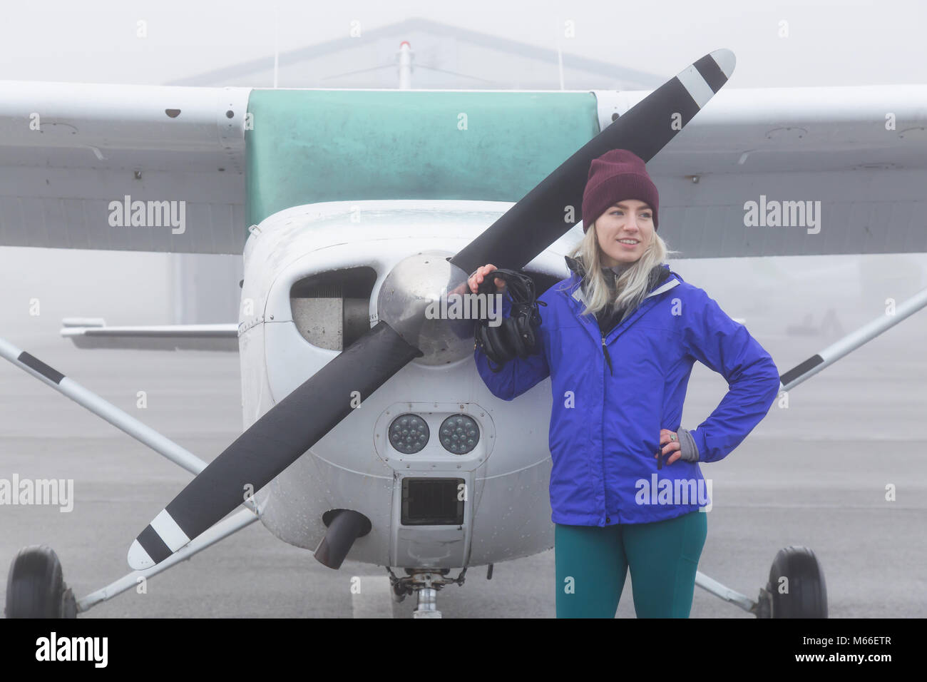 Young Caucasian Female Student Pilot is standing in front of a Single ...