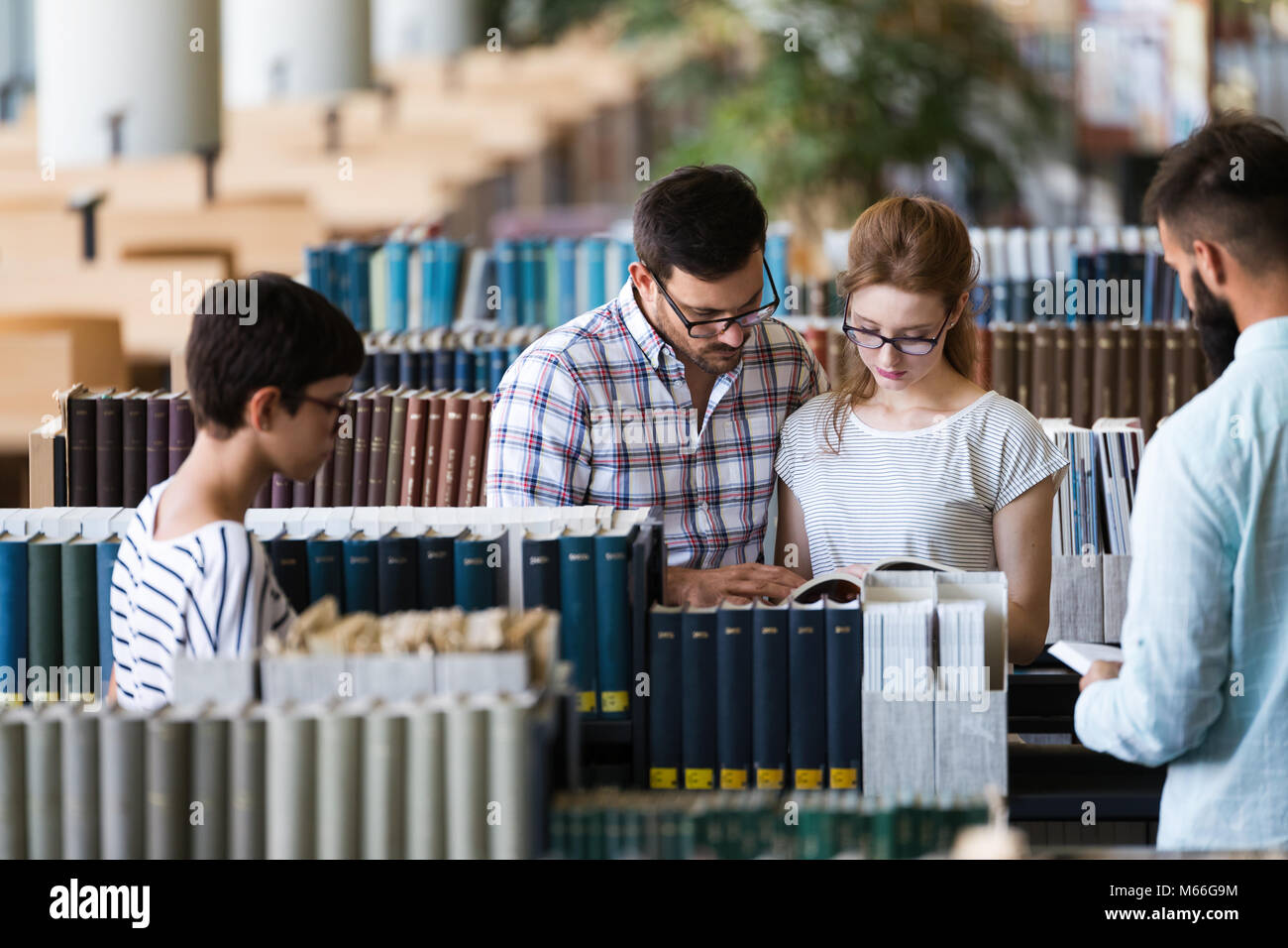 Happy young university students studying with books in library Stock ...