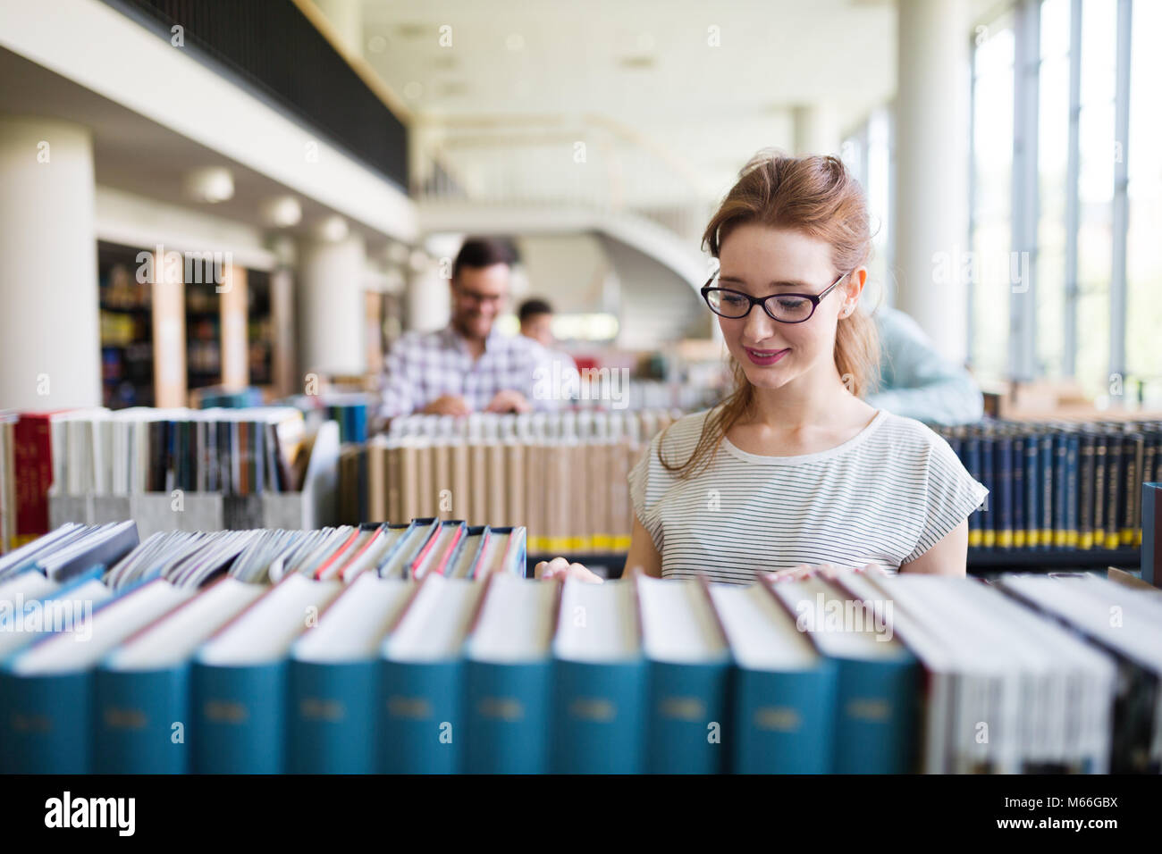Portrait of a pretty smiling girl reading book in library Stock Photo ...