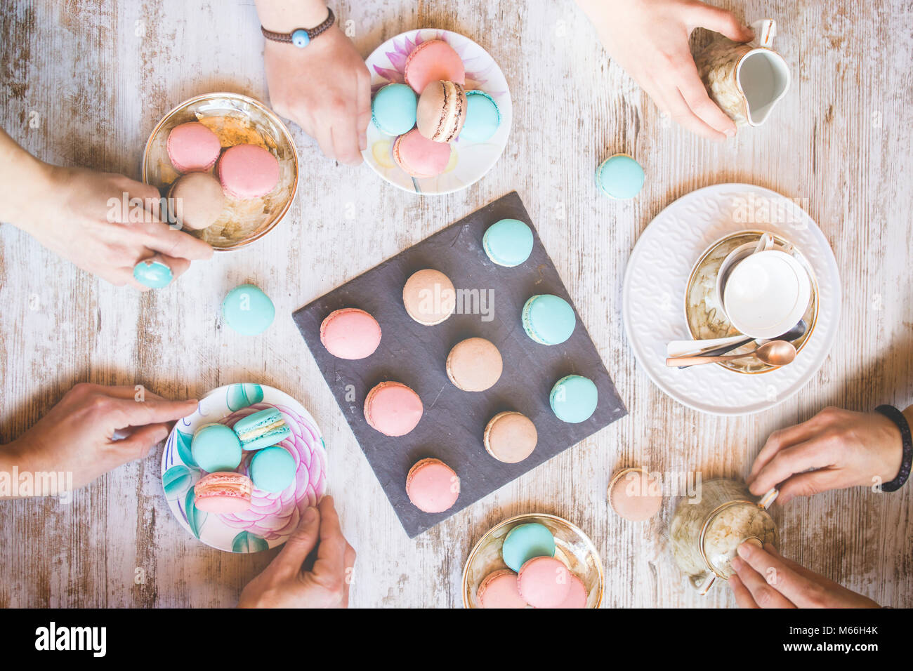 Five people sitting round a table eating macaroons Stock Photo - Alamy