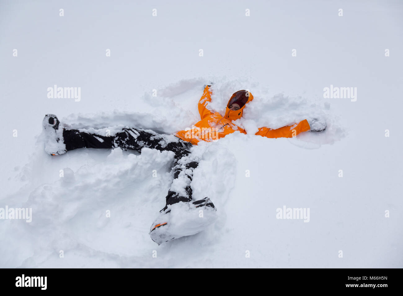 Adventure man in a colorful outfit is making snow angel. Taken in ...