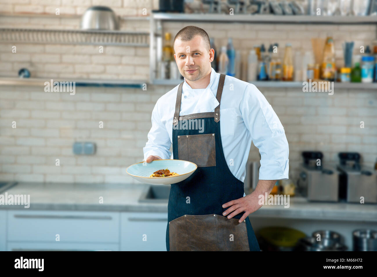 happy male chef presenting the dish in commercial kitchen interior ...