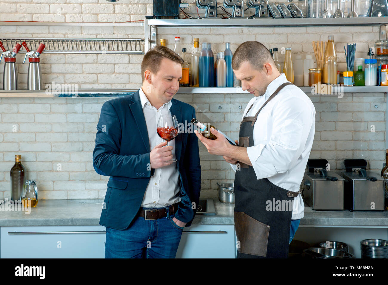 sommelier and chef discuss wine on the kitchen interior. the sommelier ...
