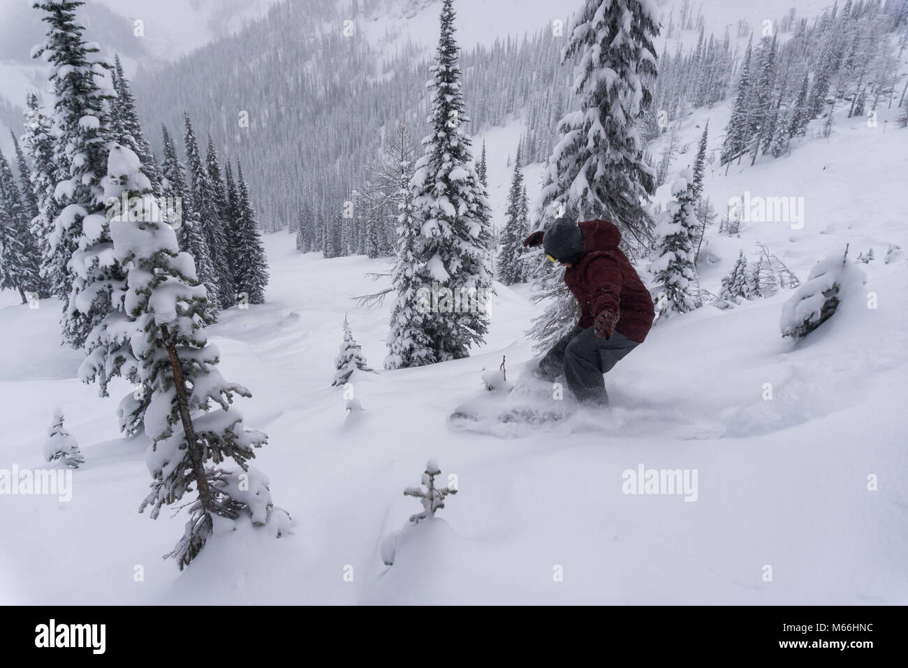 Male snowboarder riding white powder snow in the extreme terrain. Taken ...