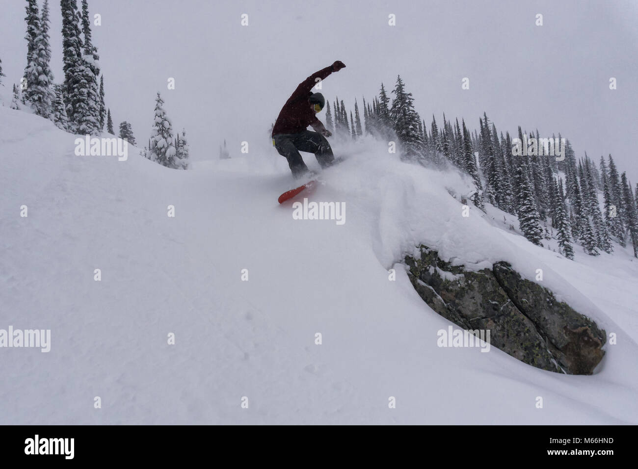 Male snowboarder riding white powder snow in the extreme terrain. Taken ...