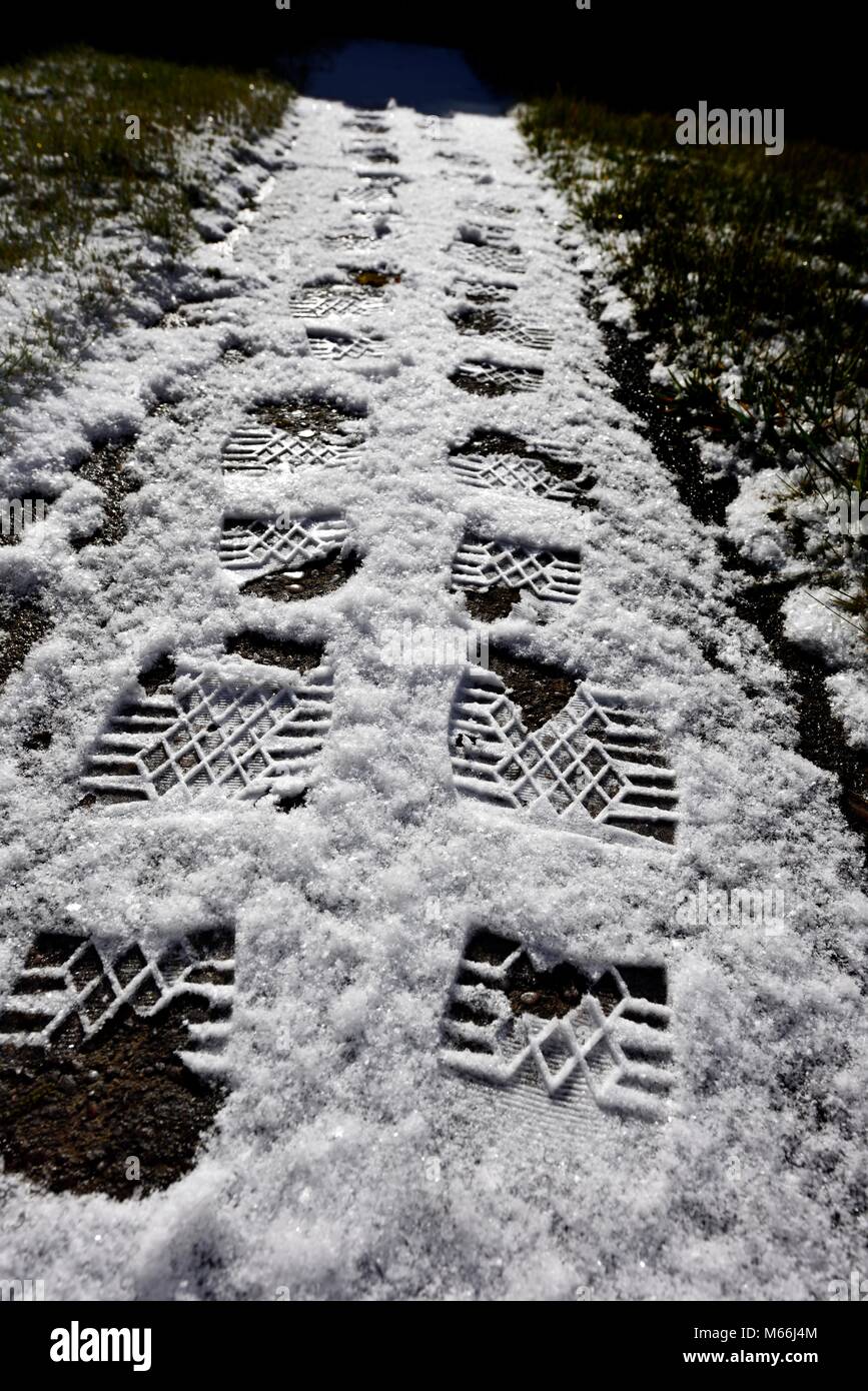 Boot Footprints in the snow going up a footpath Stock Photo - Alamy