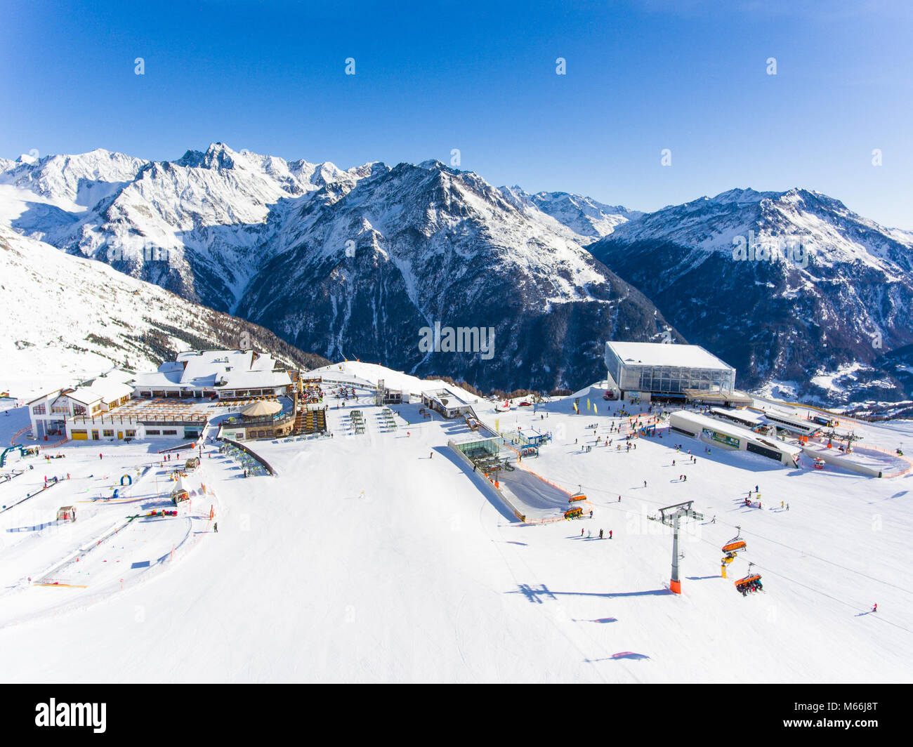 Ski resort in the Alps with ski lift and people skiing on the slope ...