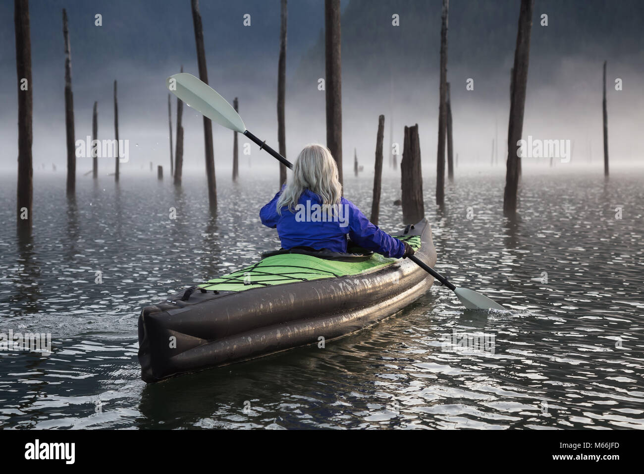 Adventurous Girl kayaking on an infatable kayak in a beautiful lake ...