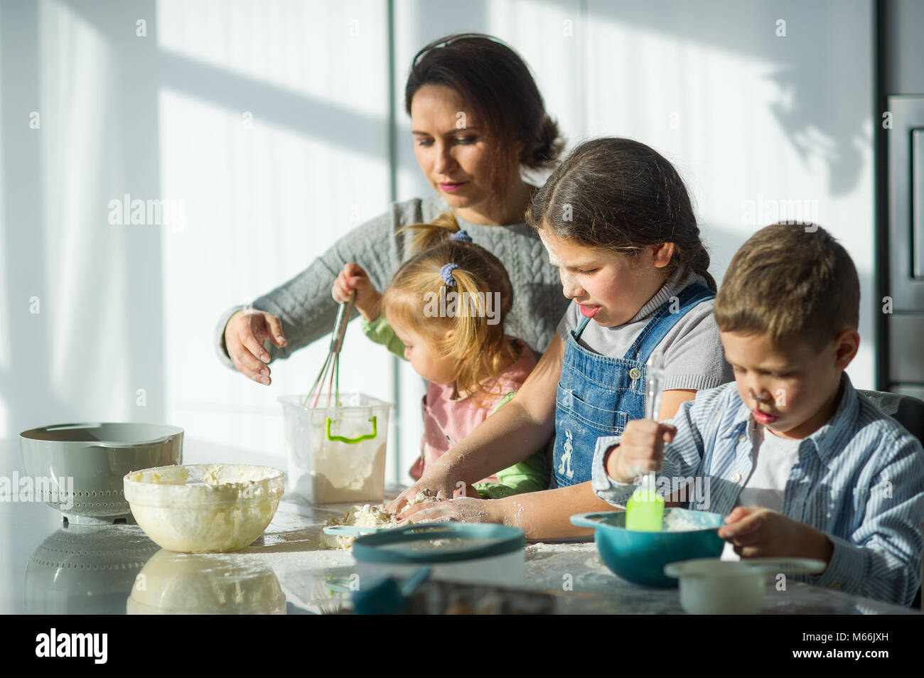 Mother teaches her three children to cook. Family is preparing ...