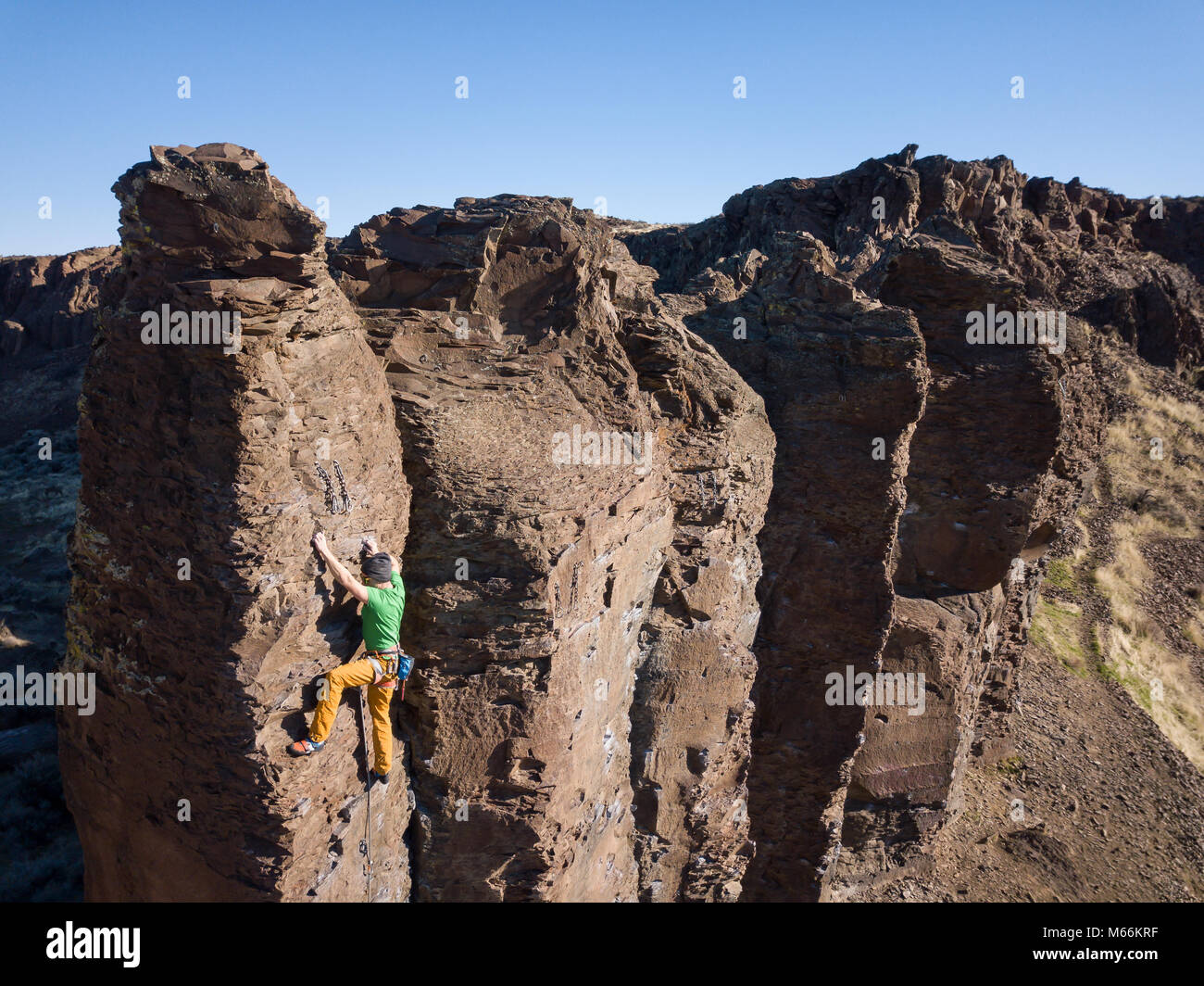 Aerial view of a rock climber climbing a steep cliff during a sunny ...