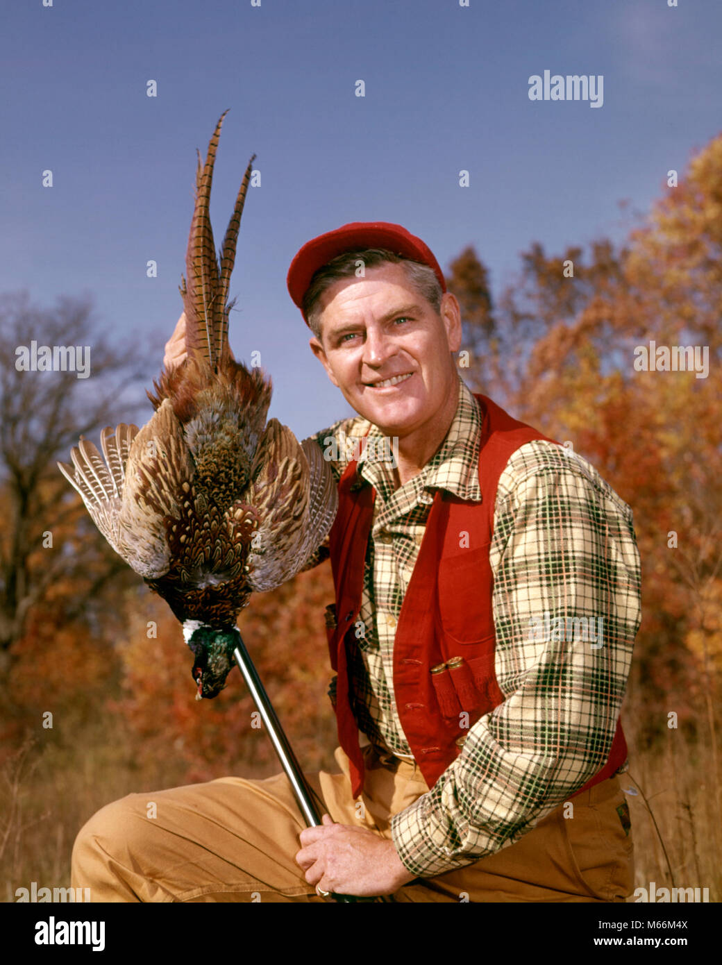 1960s SMILING MAN HUNTER LOOKING AT CAMERA HOLDING UP HARVESTED ...