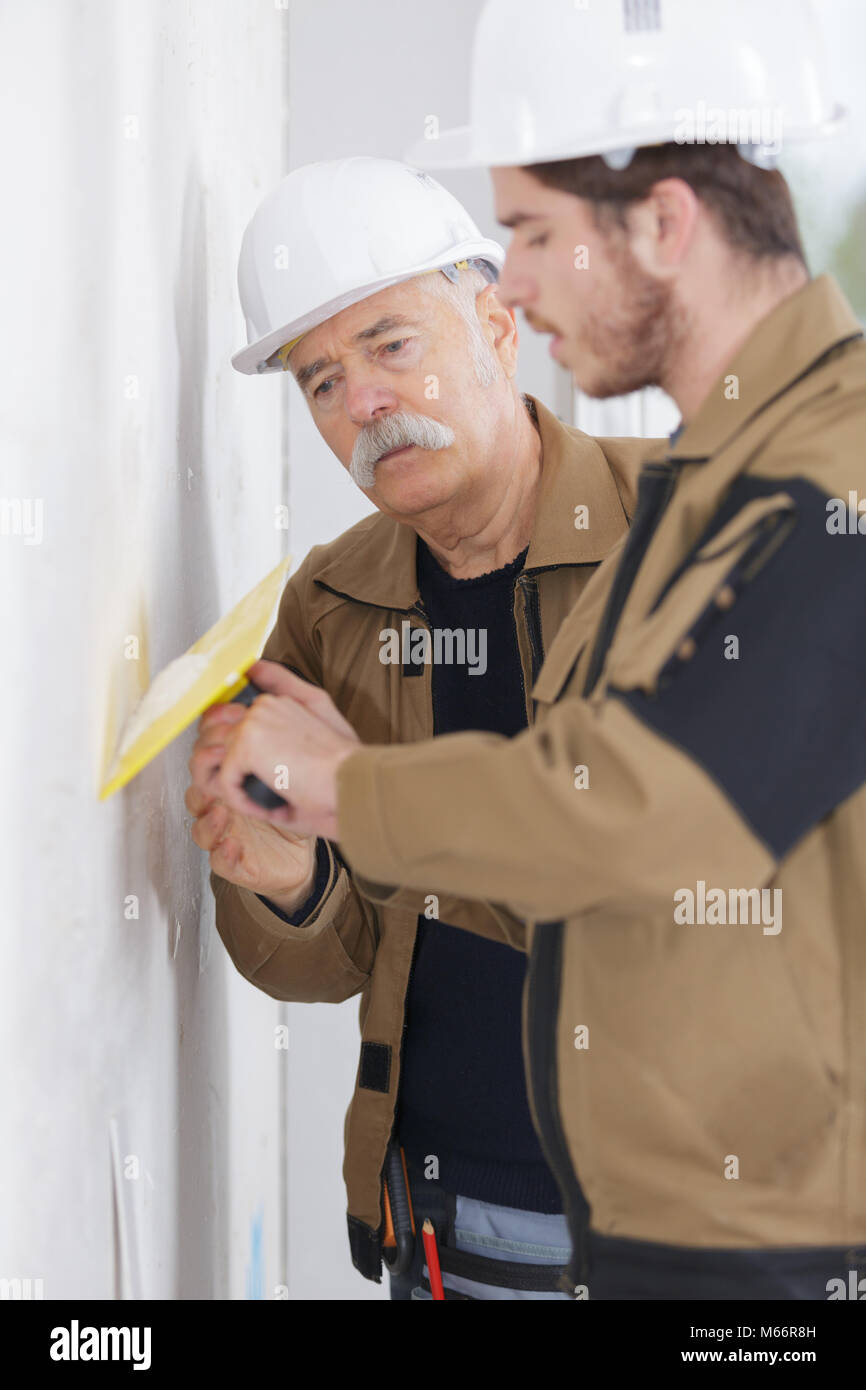young apprentice with professional plasterer Stock Photo - Alamy