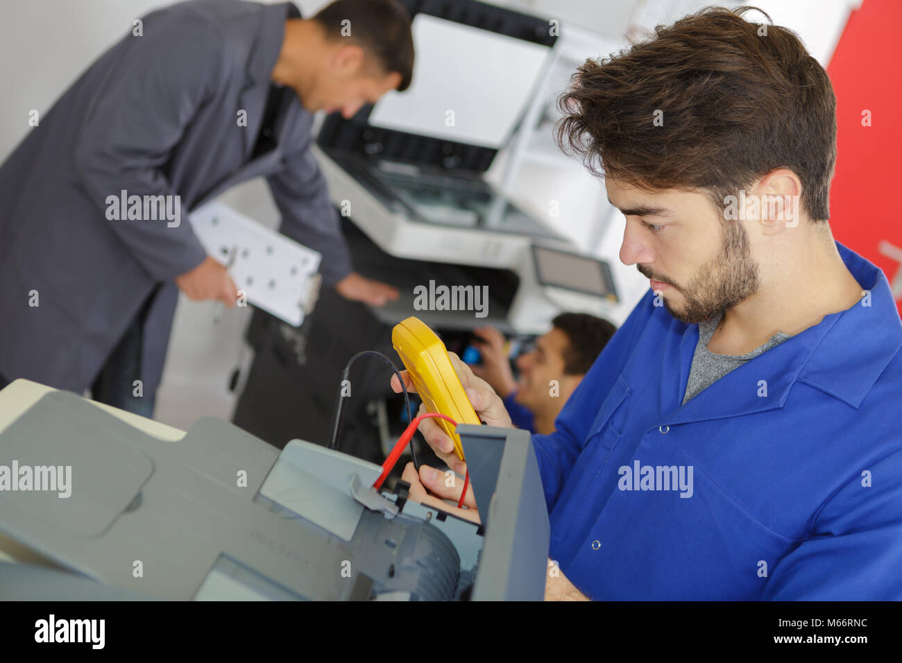 young man measuring voltage in service center Stock Photo - Alamy