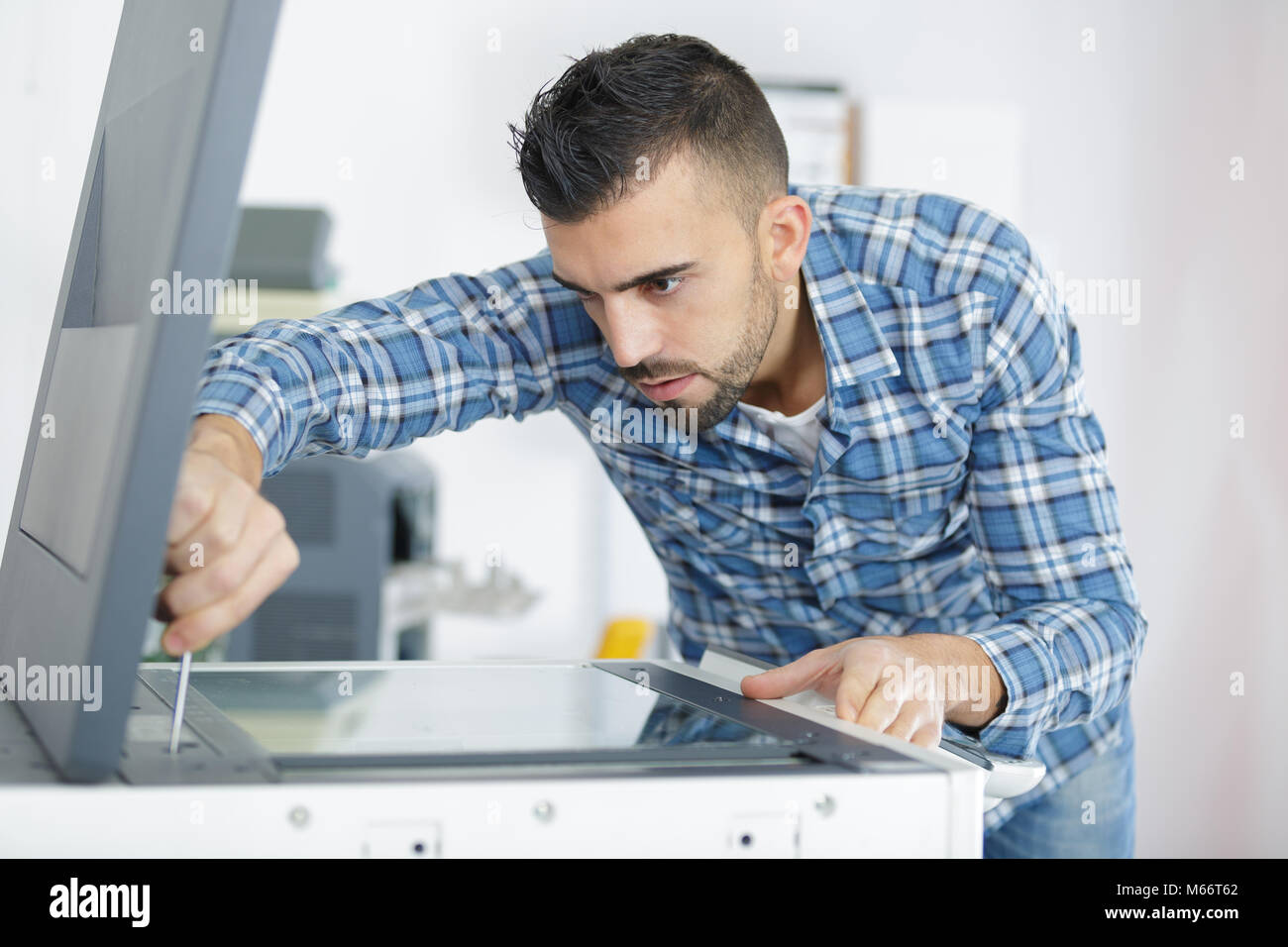 man repairing photocopier using screwdriver Stock Photo - Alamy
