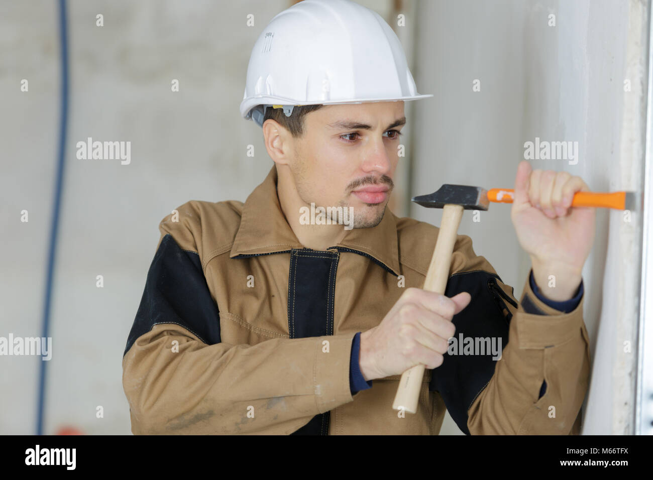 young builder holding chisel and hammer Stock Photo - Alamy