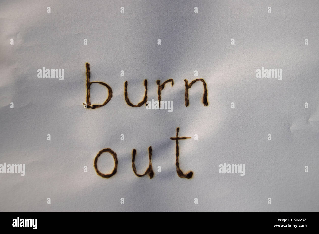 words burn out have been burnt into white paper Stock Photo - Alamy