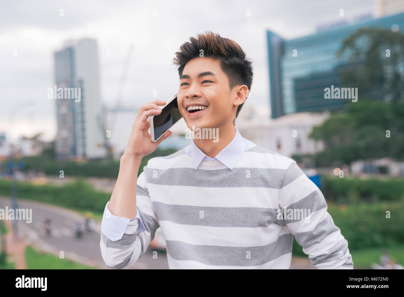 Portrait of handsome young man in city talking on smartphone Stock ...