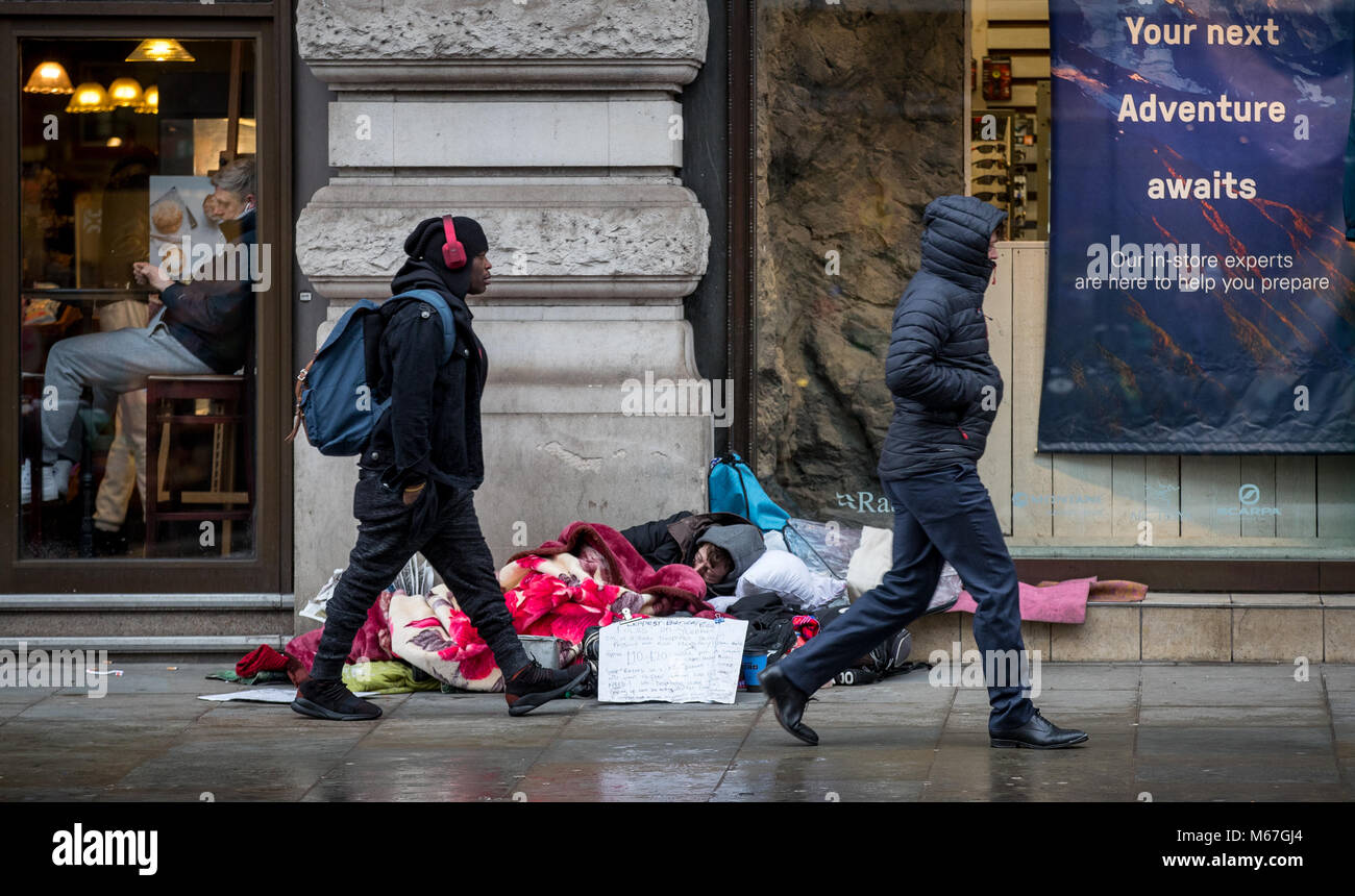 London, UK. 1st March, 2018. A homeless man lays in the cold with a ...