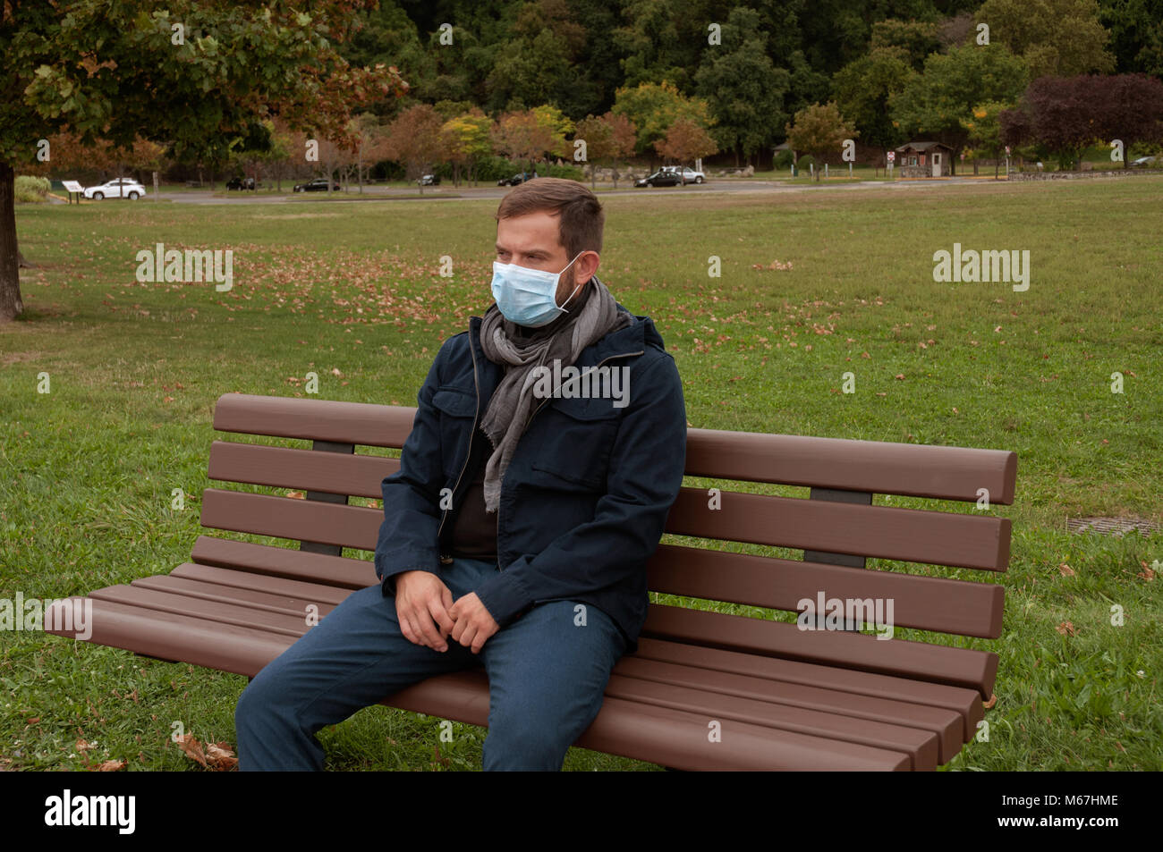 Man has cold or flu. Man has catch cold is sitting on bench in the park ...