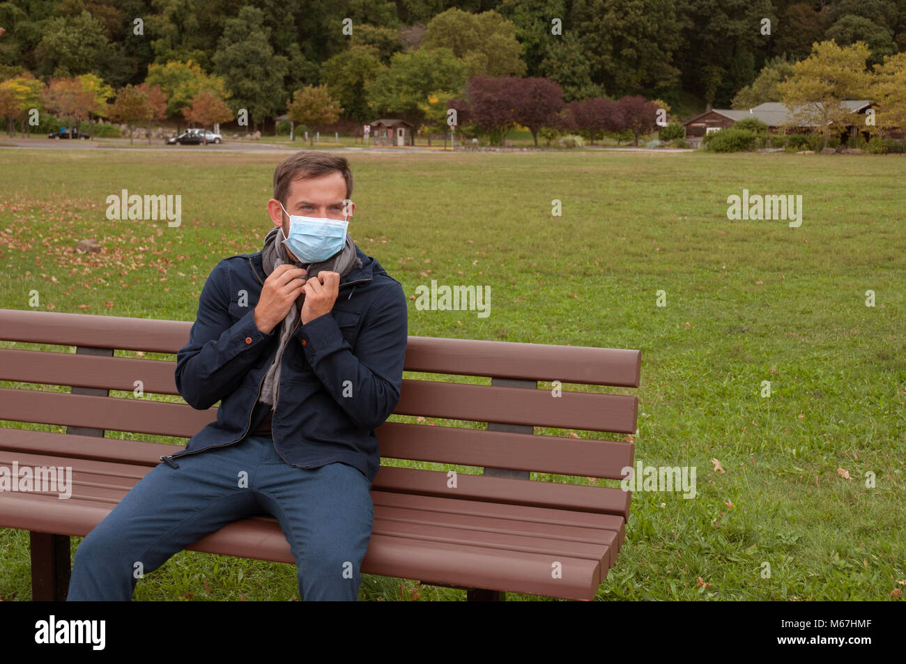 Man has cold or flu. Man has catch cold is sitting on bench in the park ...