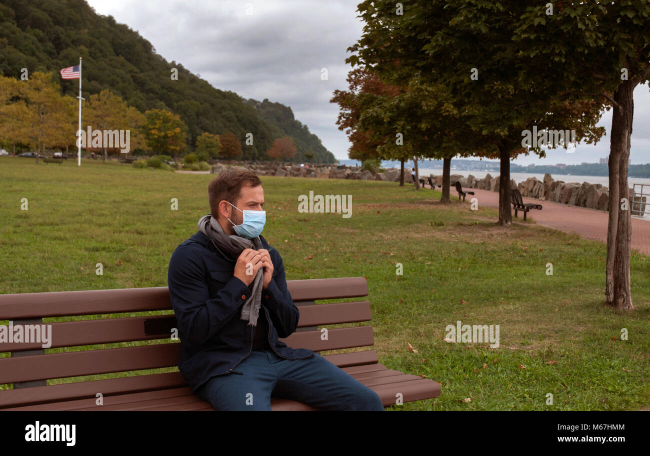 Man has cold or flu. Man has catch cold is sitting on bench in the park ...