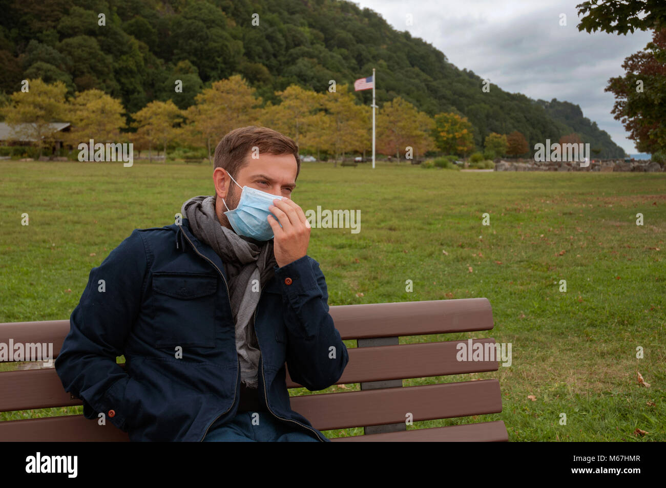Man has cold or flu. Man has catch cold is sitting on bench in the park ...