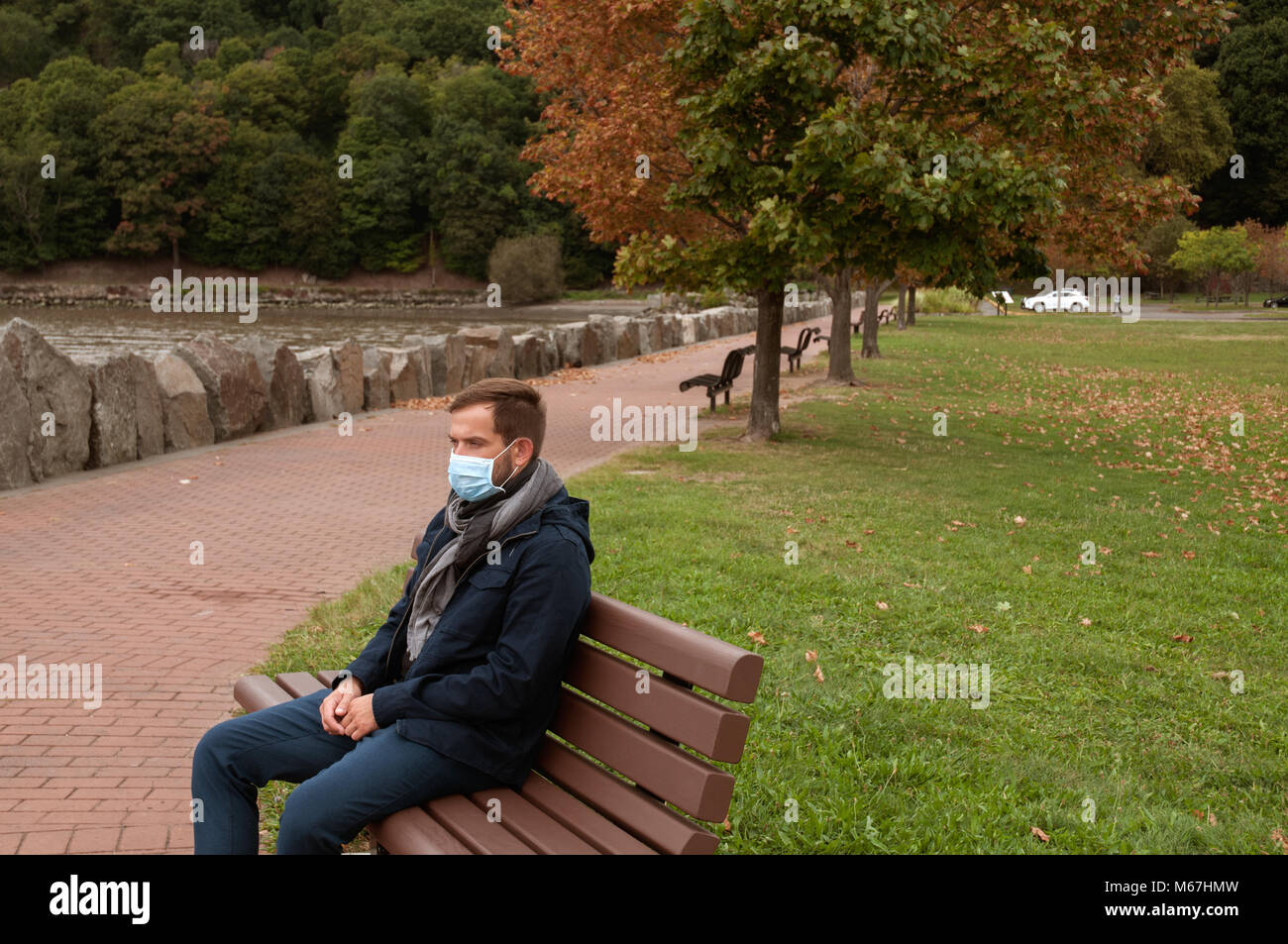 Man has cold or flu. Man has catch cold is sitting on bench in the park ...