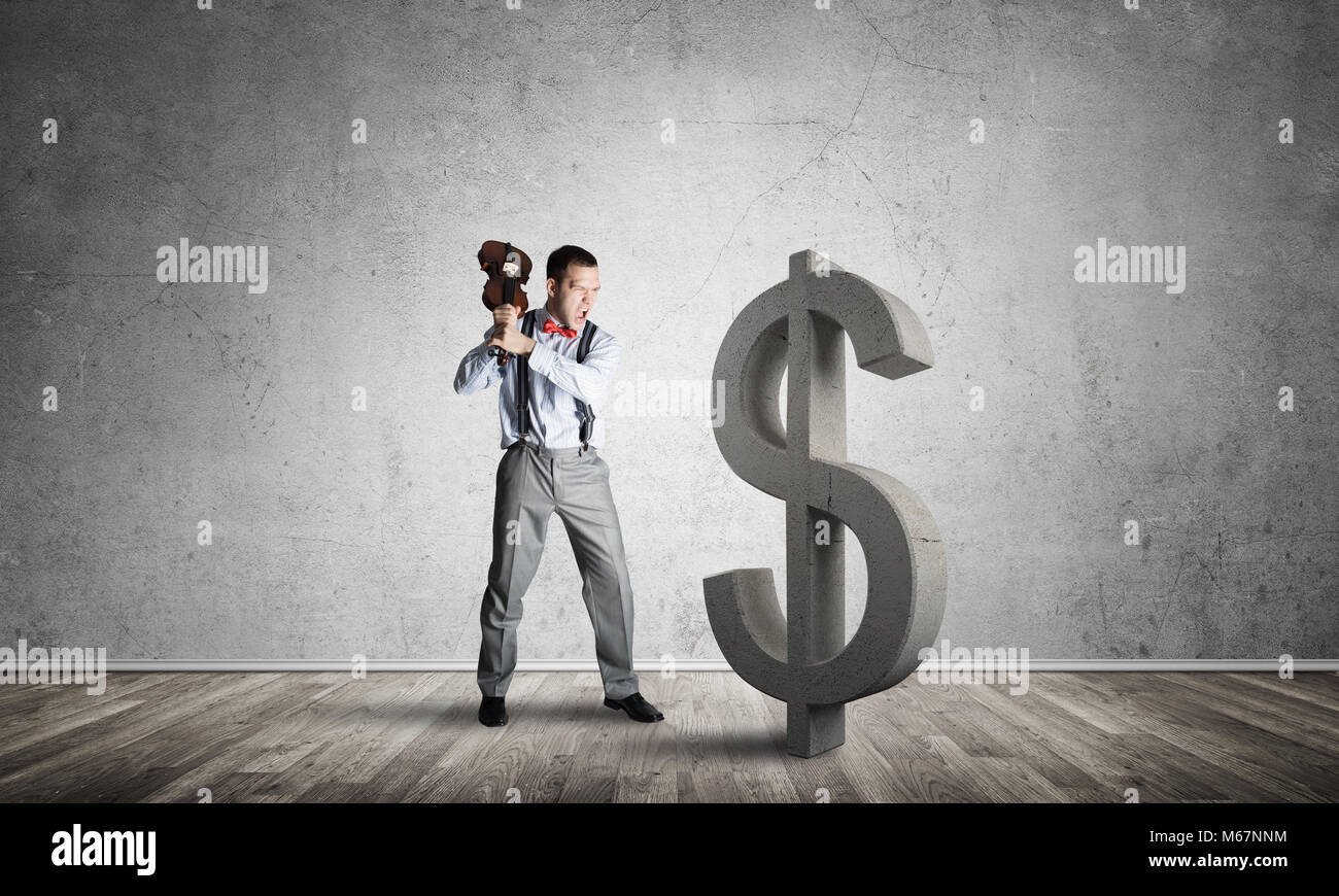 Determined banker man in empty concrete room breaking dollar figure ...