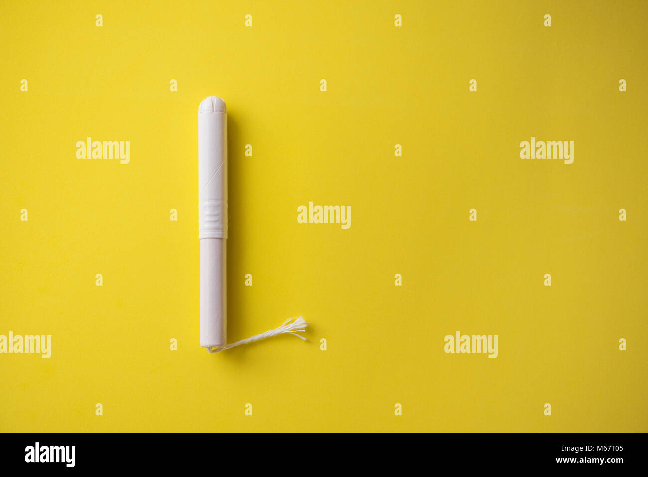 Feminine tampon with paper applicator on yellow background Stock Photo ...