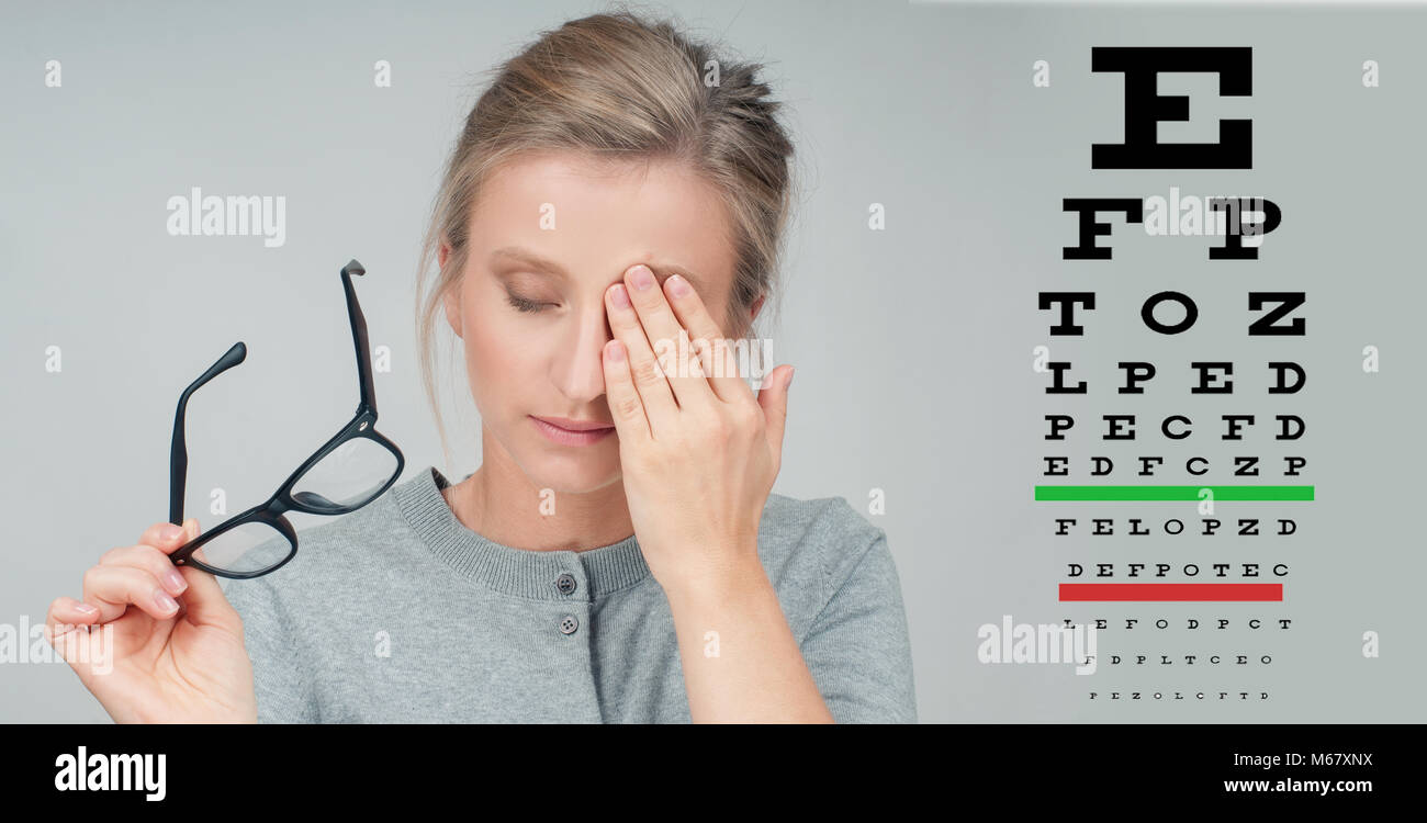 Woman in glasses reviewing eyesight closing eye with hand. Eye test ...