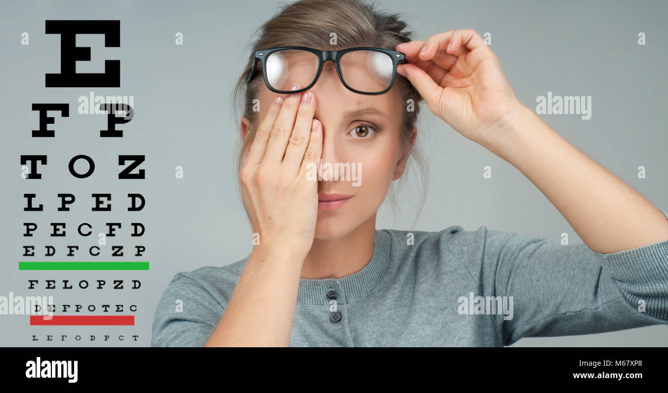 Woman in glasses reviewing eyesight closing eye with hand. Eye test ...