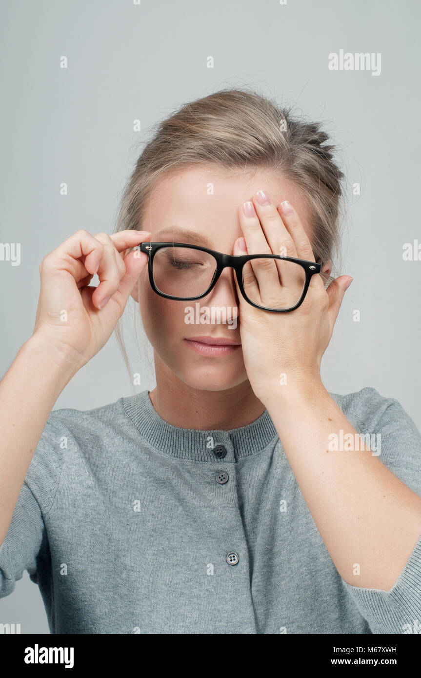Tired woman in eyeglasses with eyes pain, covering eyes with hands ...