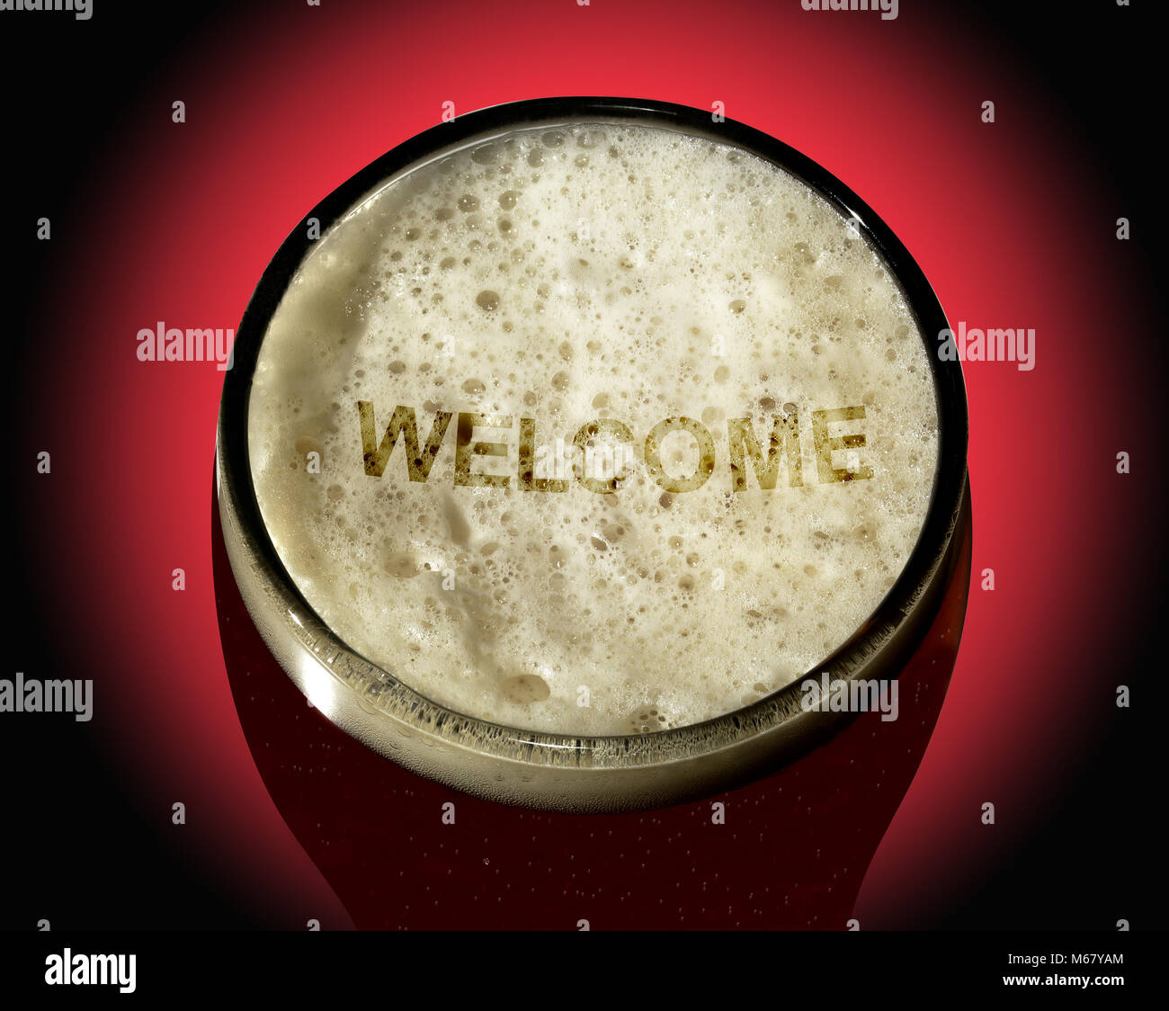 A glass of dark beer with the word 'Welcome' written in the foam, shown ...
